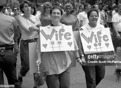 25th June 1989: Two women wearing "Wife" signs around their necks ...