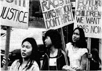 Demonstrators march outside Chinatown with signs.