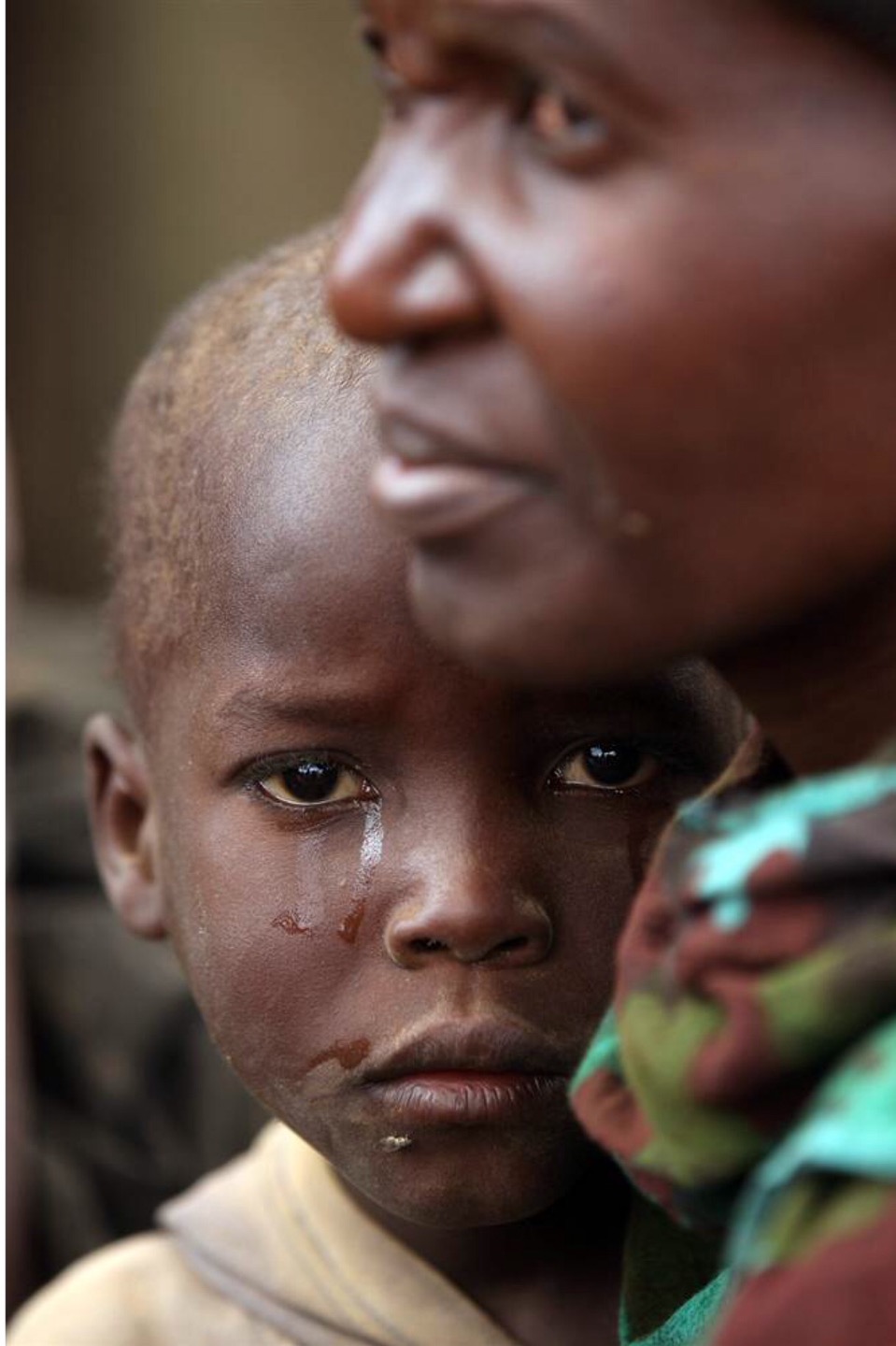This is an image of a refugee boy crying on his fathers soulder.