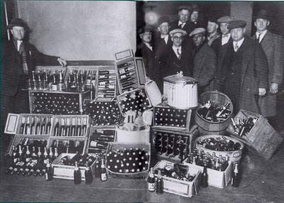 Men standing around seized alcohol during prohibition.