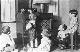 Picture of children gathered around the radio. The radio was the center ...