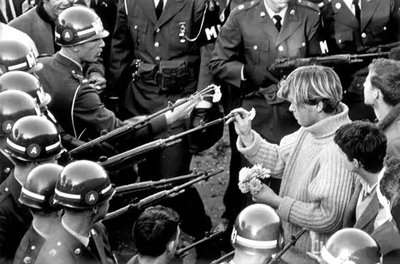 An antiwar demonstrator places flowers into the barrels of rifles while ...